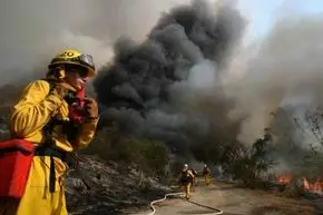 Firefighter Elizabeth Ferolito ngajaga hiji panon dina backfire dikawasa di Irvine, California, diatur ngajaga homeowners sakumaha wildfire a rages.