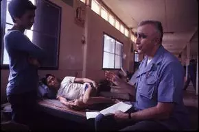 Dr Amos Townsend, pensiunan Kolonél Angkatan Udara AS ngawawancara korban Laos tina hujan konéng di Ban Vinai Refugee Camp pikeun urang Hmong ngungsi meuntas wates ka timur laut Thailand, 1982.