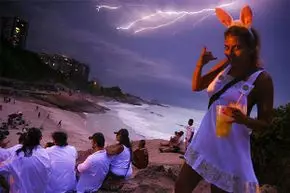 دانييلا سولاريس تمشي أمام الكاميرا بينما يضرب البرق فوق شاطئ كوباكابانا خلال مهرجان الكرنفال في البرازيل ؛ قد ترغب في التعامل مع هذا البرق بجدية أكبر.