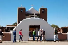 방문객들이 뉴멕시코주 타오스 푸에블로에 있는 성 제롬 교회에 입장하고 있습니다. Taos는 Taos Hum으로 알려진 기괴한 소음의 고향입니다.