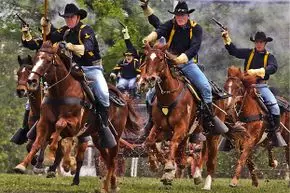 गनपाउडर और गंदगी हवा में लटकी हुई है क्योंकि अमेरिकी सेना की पहली कैवेलरी डिवीजन घोड़े की टुकड़ी ने 25 मार्च, 2009 को फोर्ट हूड, टेक्सास में एक समारोह का समापन करने के लिए अपना पारंपरिक 'कैवेलरी चार्ज' बनाया।