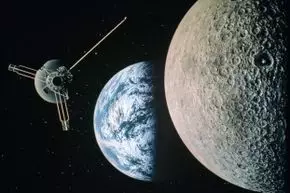 Satelit ngambang di luar angkasa, bulan di latar hareup sareng Bumi di latar tukang.