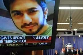 Una imagen del sospechoso de terrorismo Faisal Shahzad parpadea en una pantalla de televisión mientras el fiscal general de EE. UU. Eric Holder (centro) y otros funcionarios realizan una sesión informativa sobre la investigación del intento de atentado con bomba en Times Square.