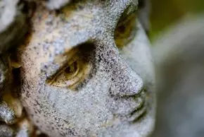 La lluvia ácida puede devorar la piedra y el metal. Ha acelerado el proceso de desgaste natural de la cara de este ángel de piedra con cicatrices.