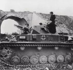 En Panzerkampfwagen IV kör genom en belgisk ruin den 17 juni 1944.