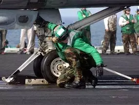 Un membre de la tripulació de la coberta de vol de l'USS George Washington revisa l'accessori de la catapulta d'un F-14 Tomcat.