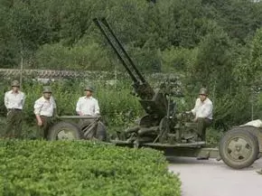 Mitarbeiter der Xiangshan Weather Modification Practice Base in Peking stehen neben einer Kanone mit zwei Rohren, die zur Regenreduzierung und Wolkenzerstreuung verwendet wird.