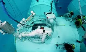 Astronaŭtoj trejnantaj en akvo por kosmopromenado por konstrui la Internacian Kosmostacion